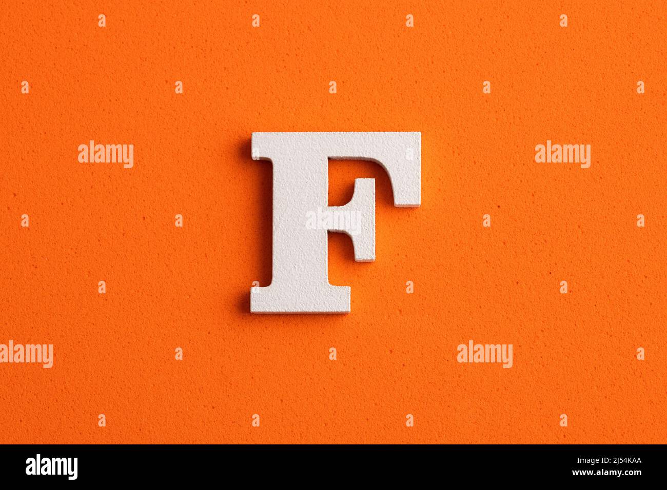 Alphabet letter F - White wood piece on orange foamy background Stock ...