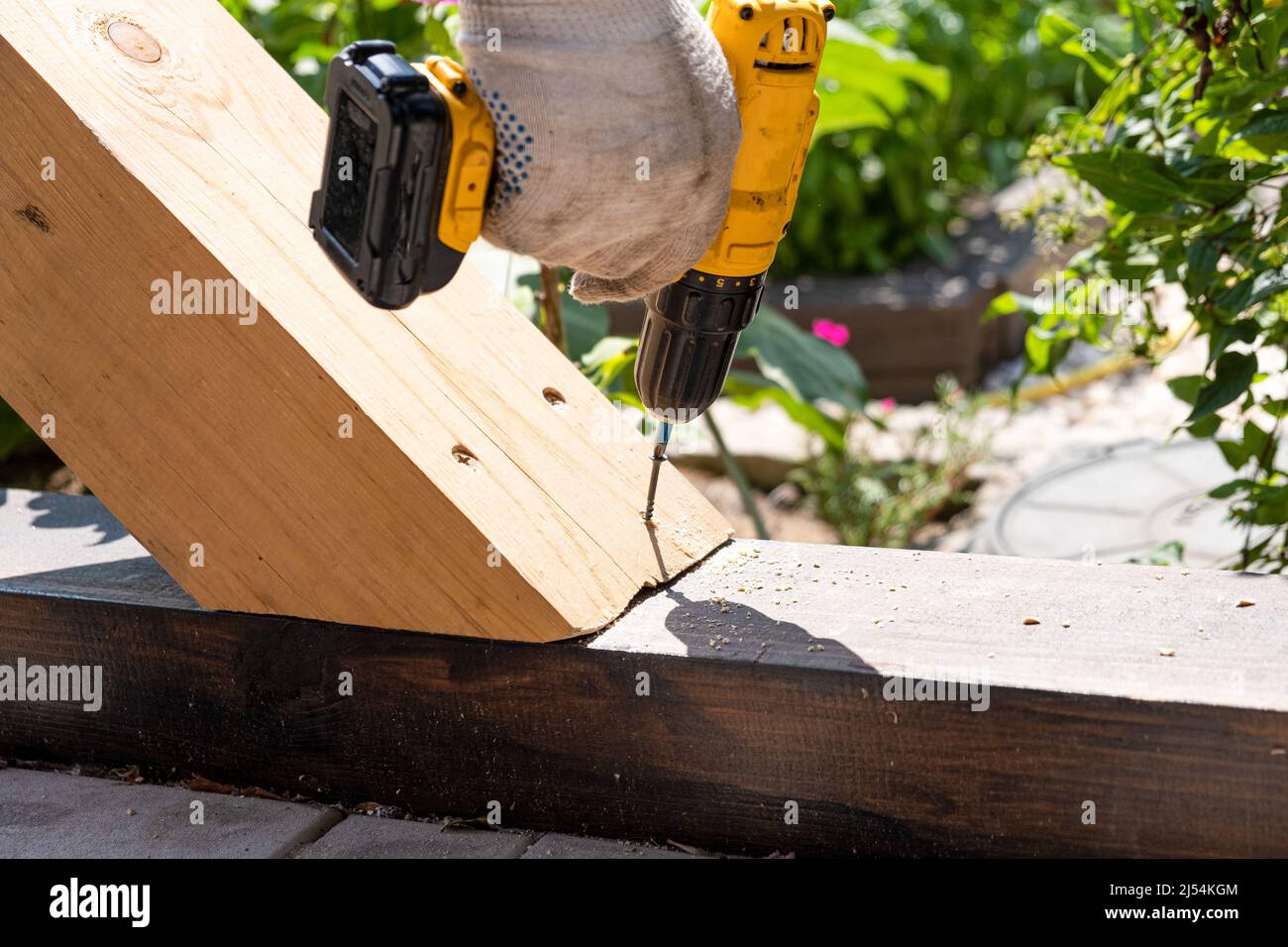 A carpenter works with a yellow electric screwdriver, twists a screw ...