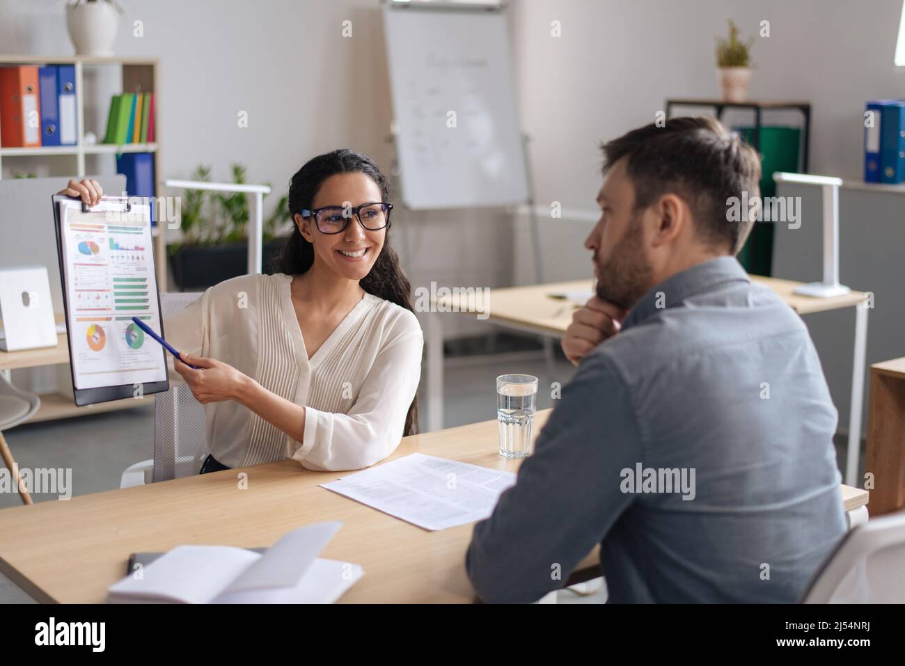 Happy young businesswoman showing chart, presenting financial report to ...