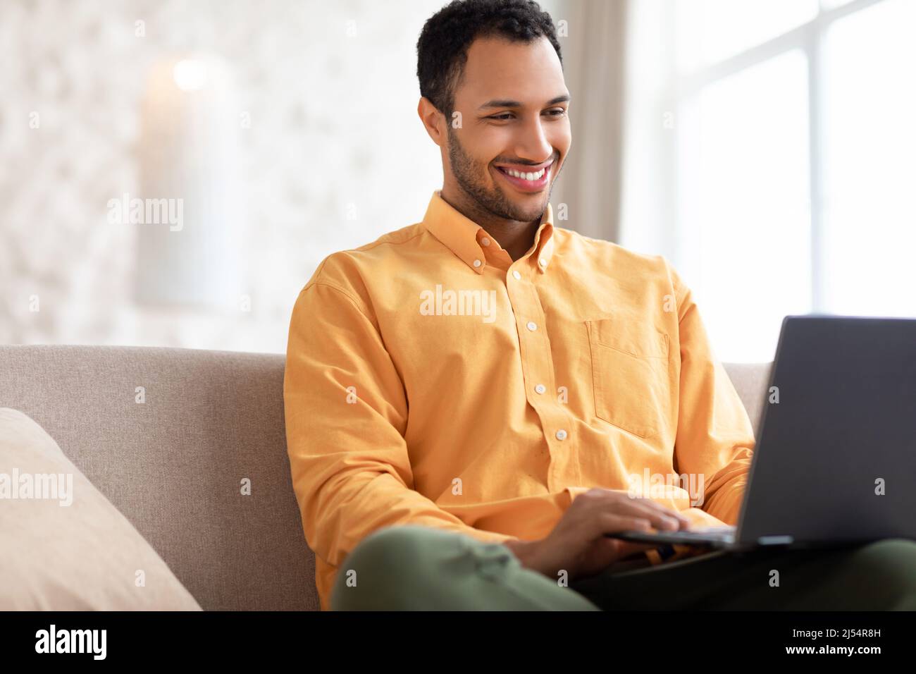 Arab man using laptop sitting on couch at home Stock Photo - Alamy