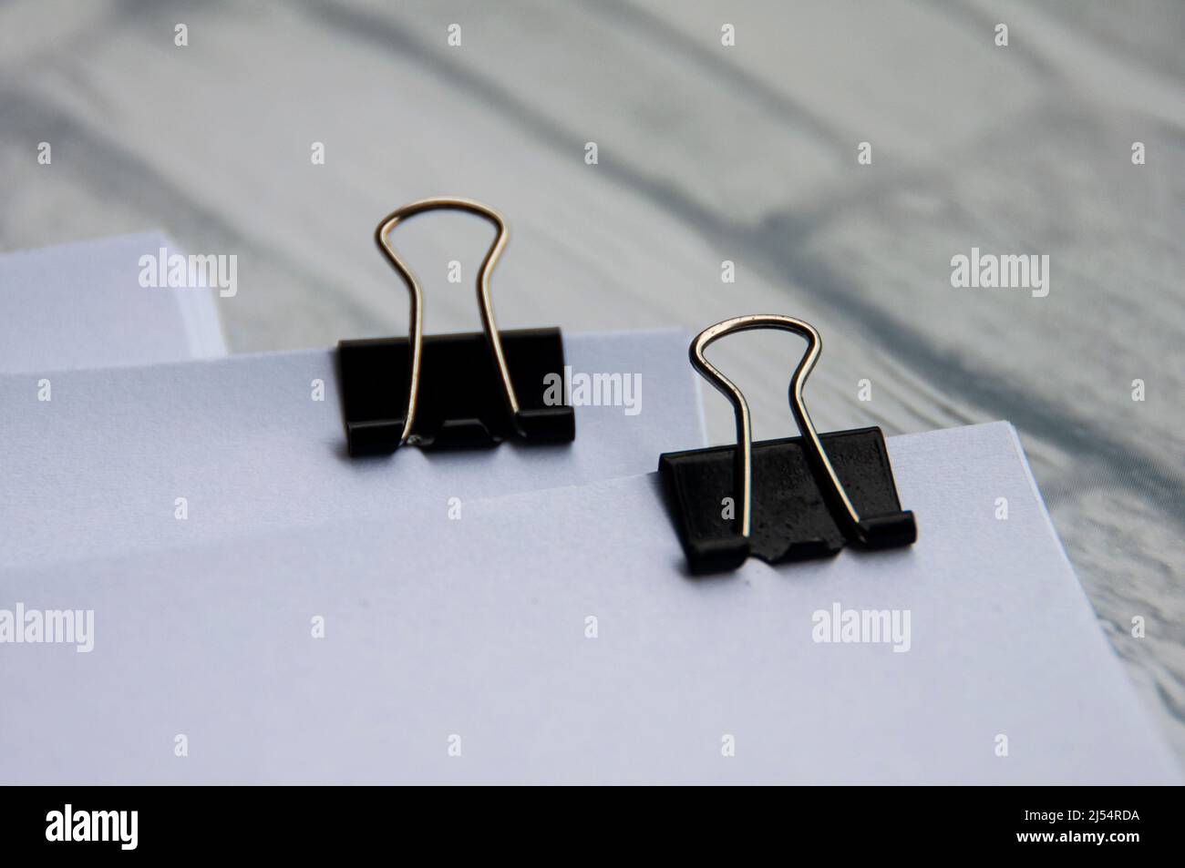Blank white paper with clip binders on white wooden table. Copy space ...