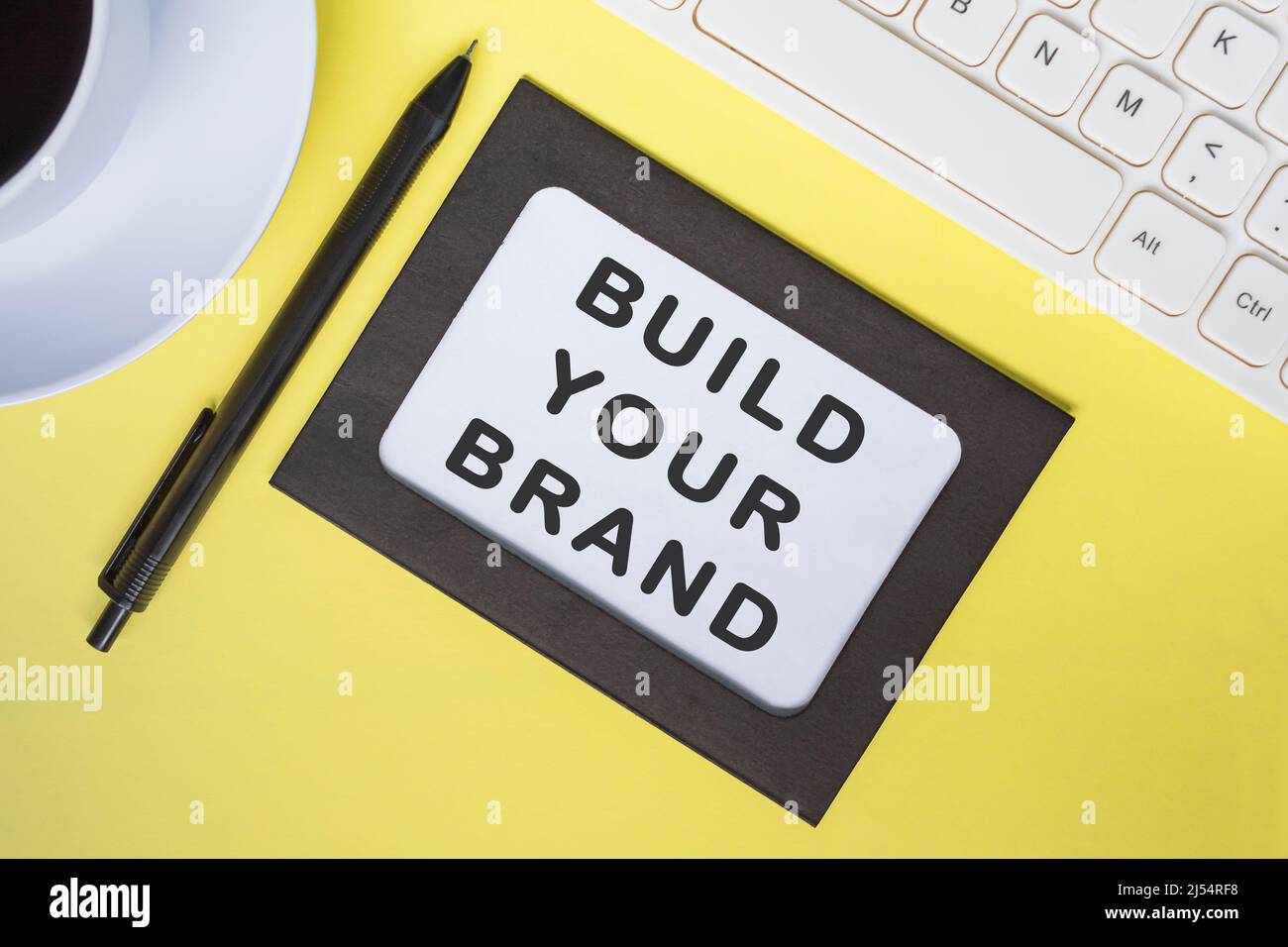 Build your brand text on white note with keyboard, pen and coffee cup ...