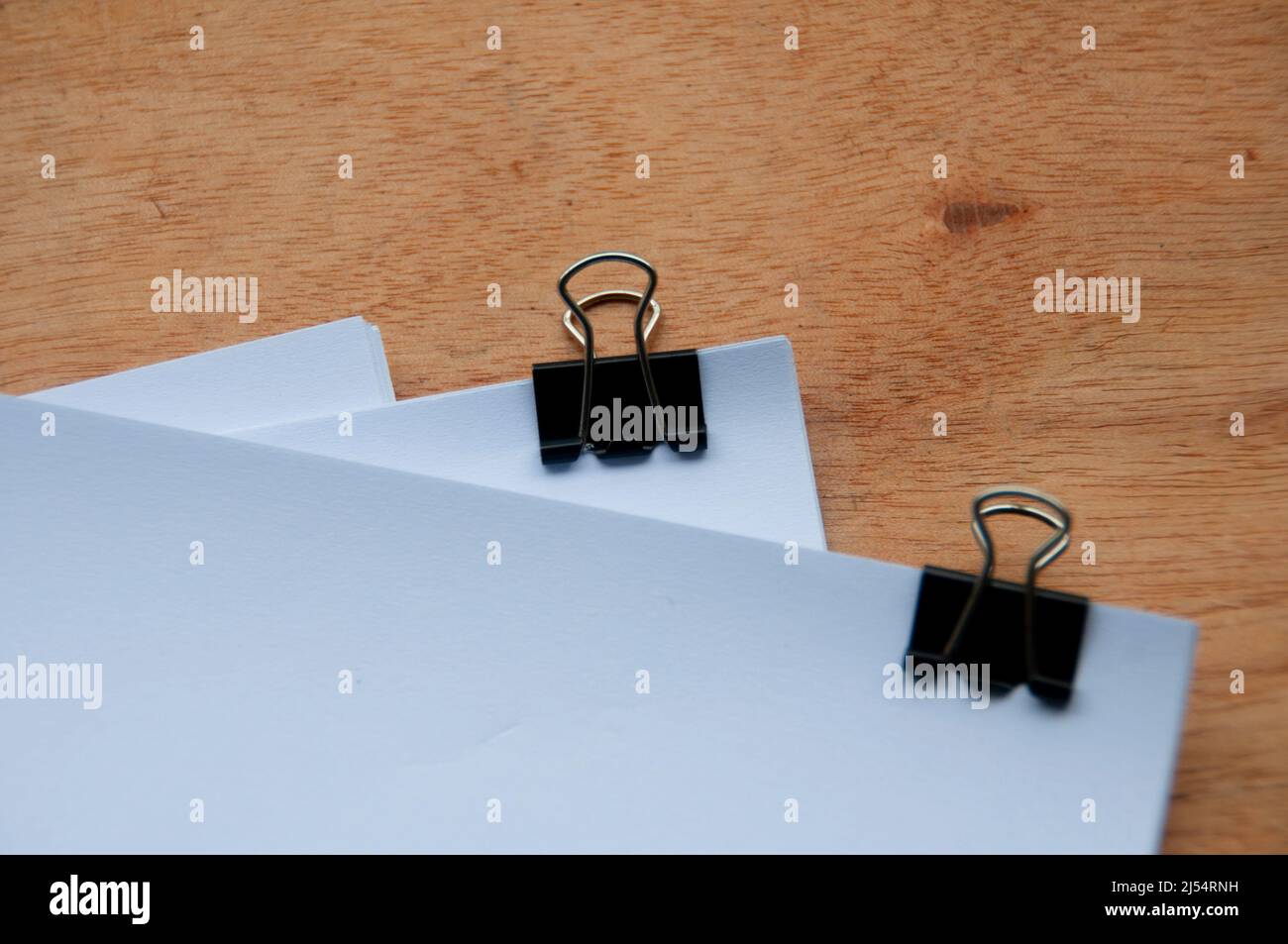 Blank white paper with clip binders on wooden table. Copy space Stock ...