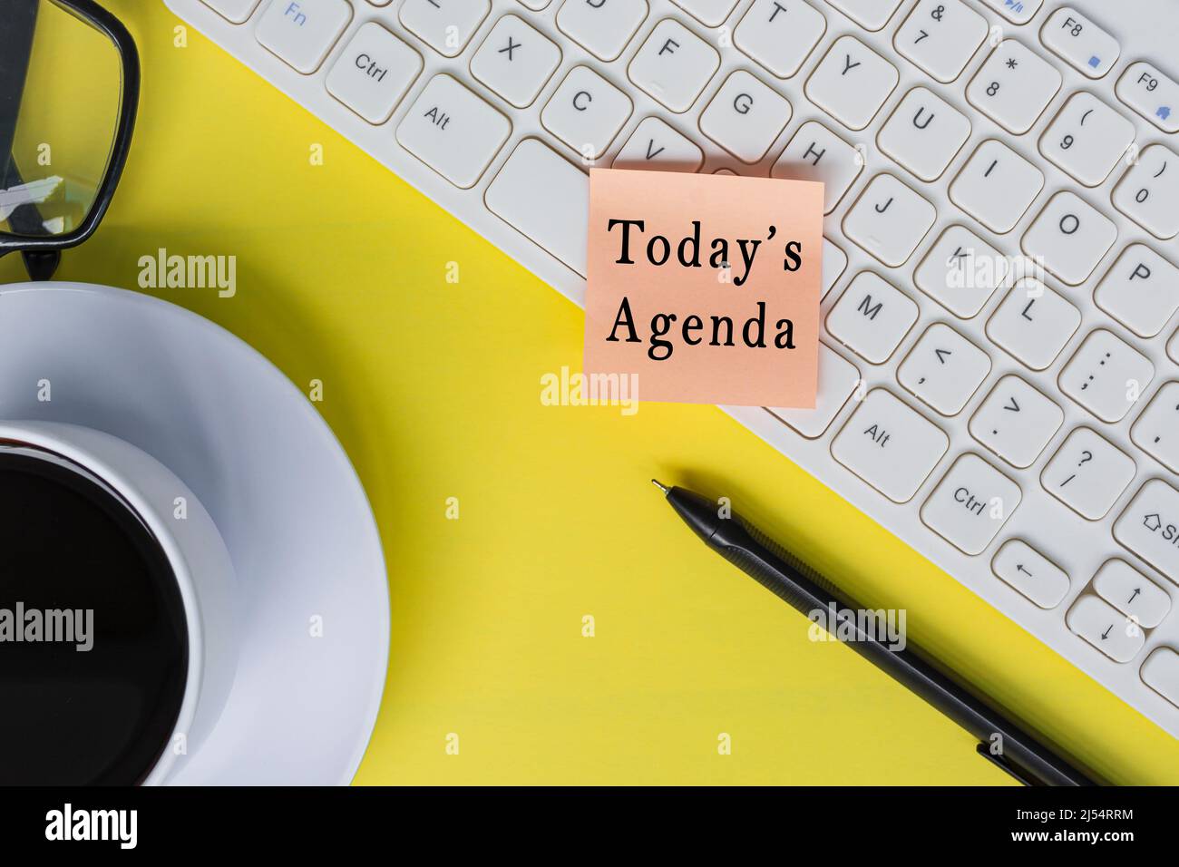Today's agenda text on sticky note with computer keyboard on yellow ...