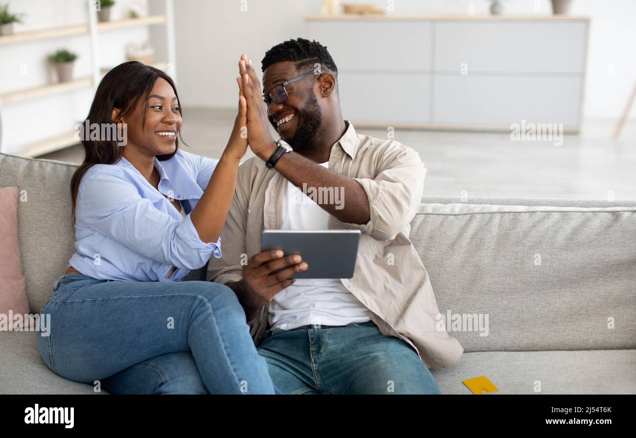Happy black couple using tablet, celebrating win giving high five Stock ...