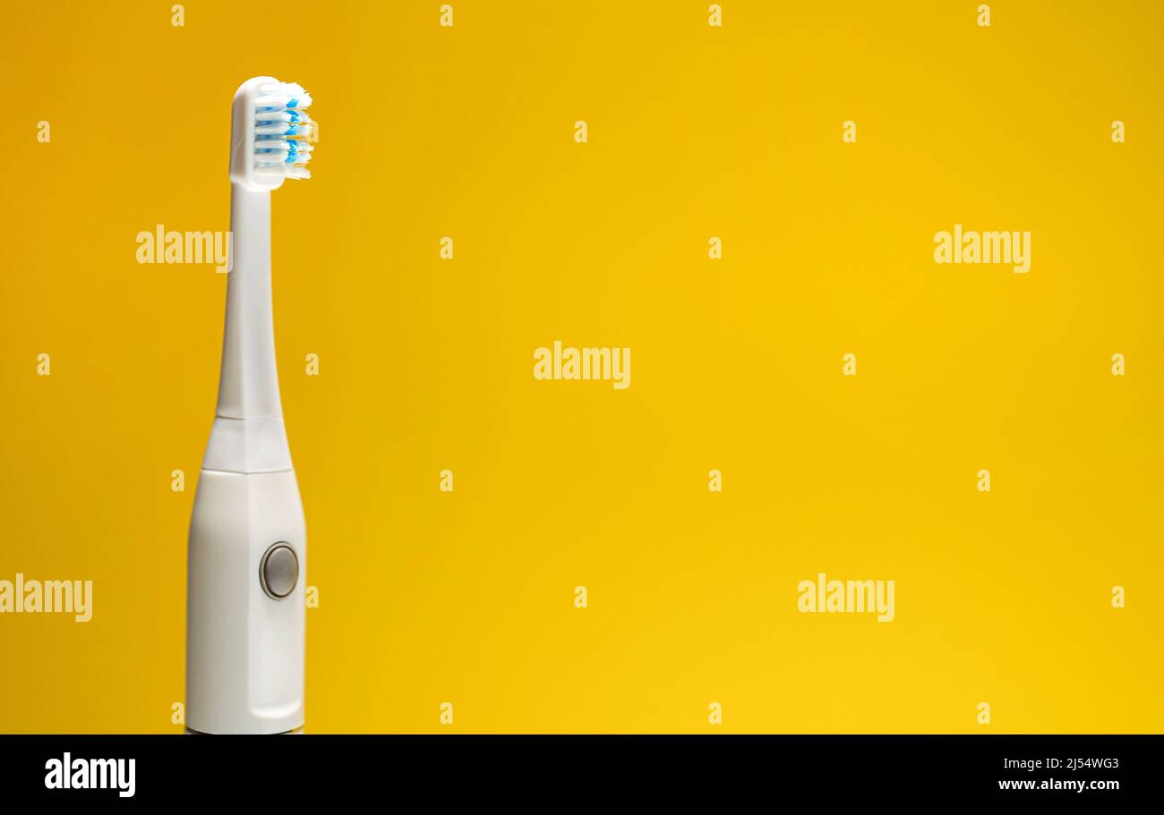 Electric ultrasonic toothbrush on yellow background Stock Photo - Alamy