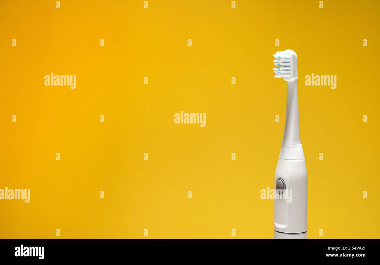 Electric ultrasonic toothbrush on yellow background Stock Photo - Alamy