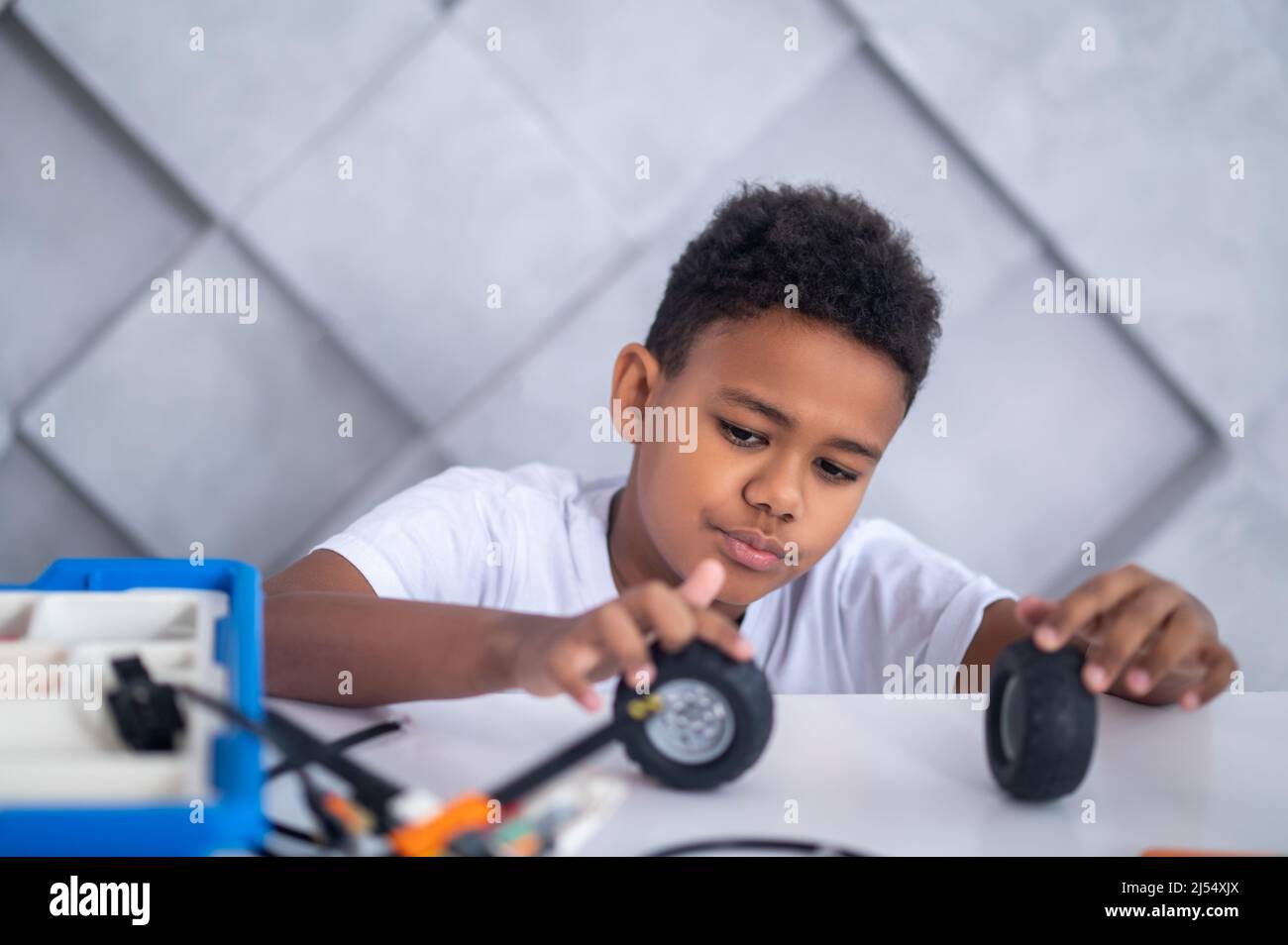 A dark-skinned boy playing with toy vehicle wheels Stock Photo - Alamy