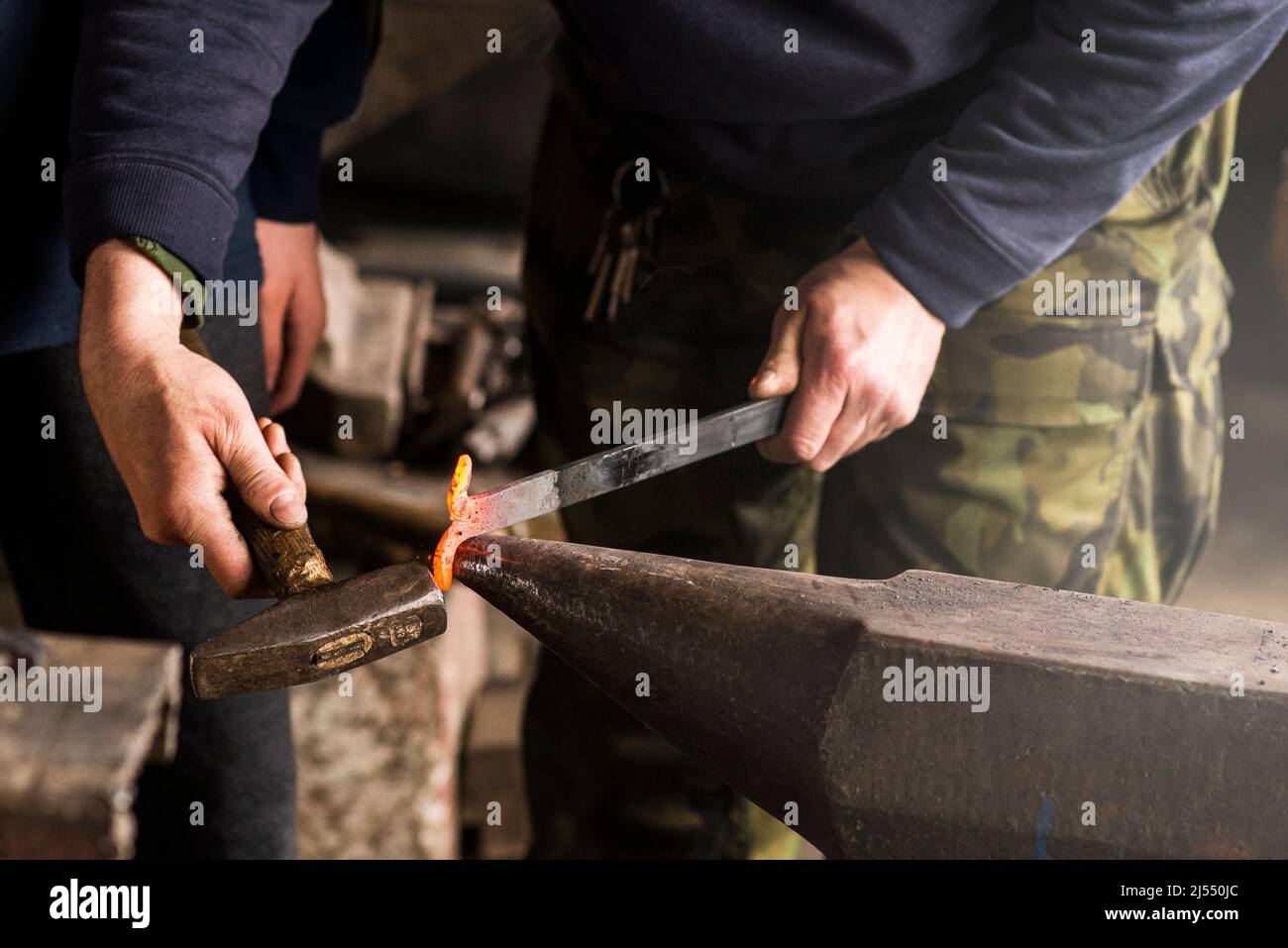 Blacksmith forges hinge on a anvil. Hammering hot red steel Stock Photo ...