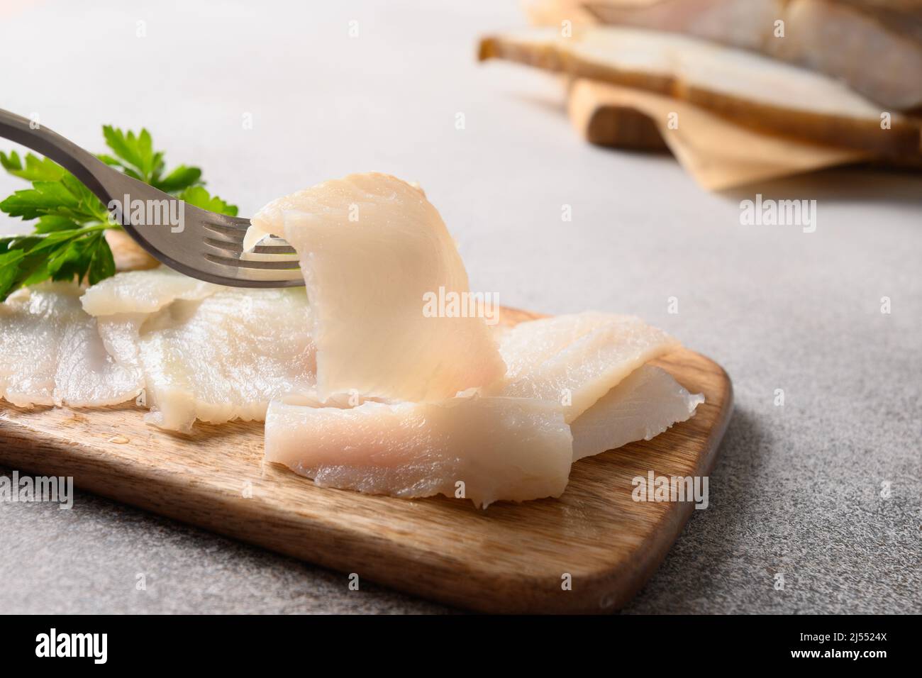 Smoked halibut slices on gray background. Man eating delicacy fish ...