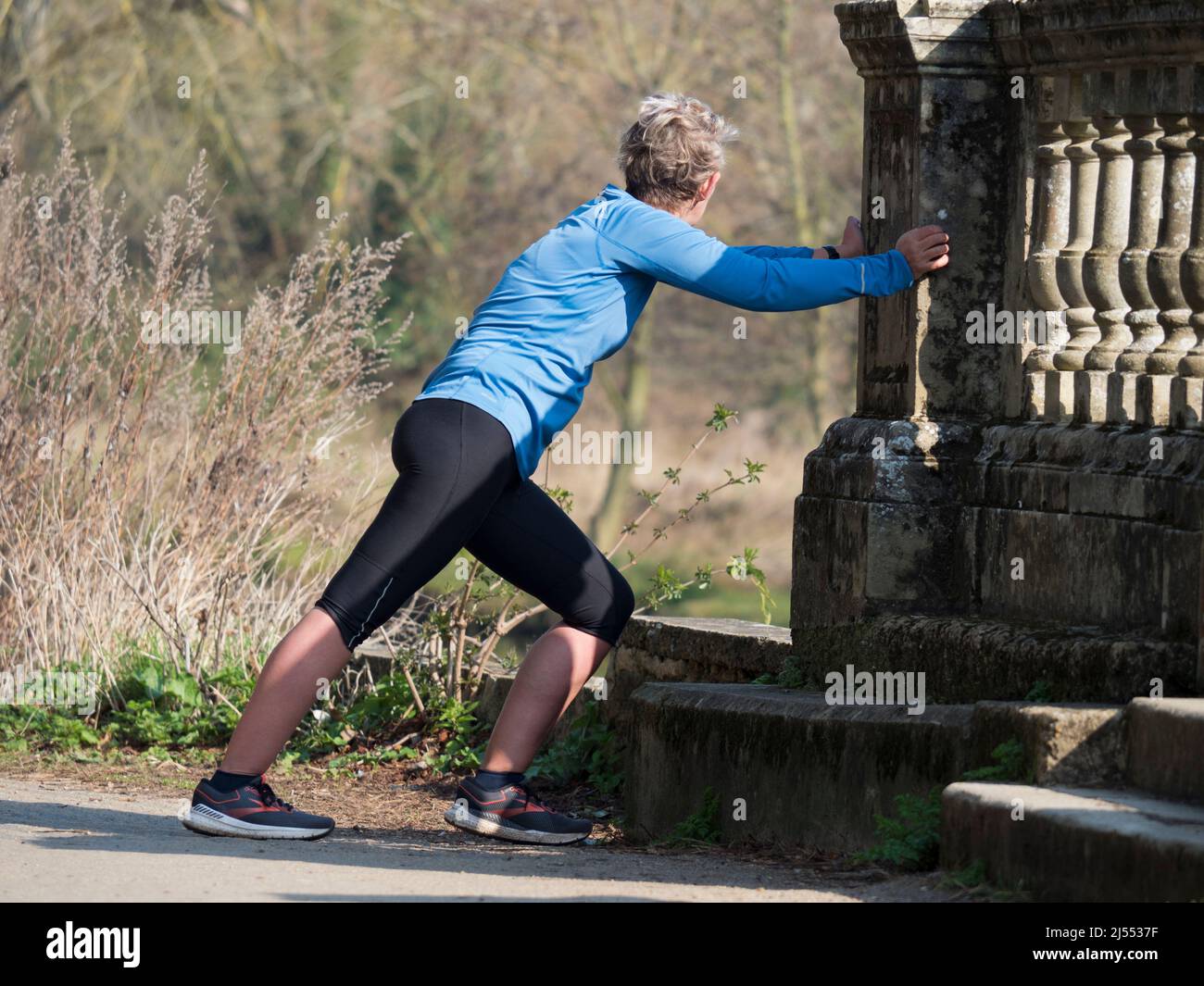 This senior woman is exercising by pushing a stone bridge which ...