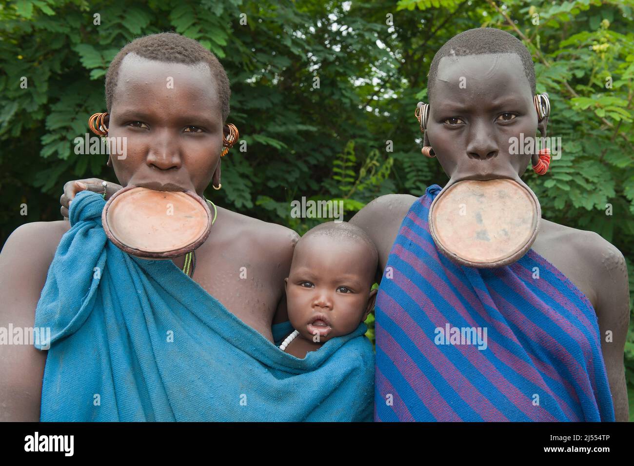 Two young Surma women with lip plate and holding a baby, Tulgit, Omo ...