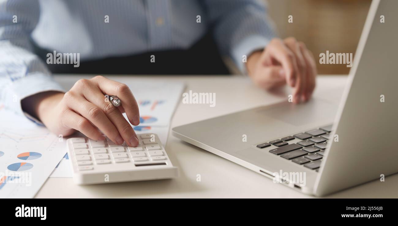 Asian Business Woman or Accountant do math and analyze with calculator ...