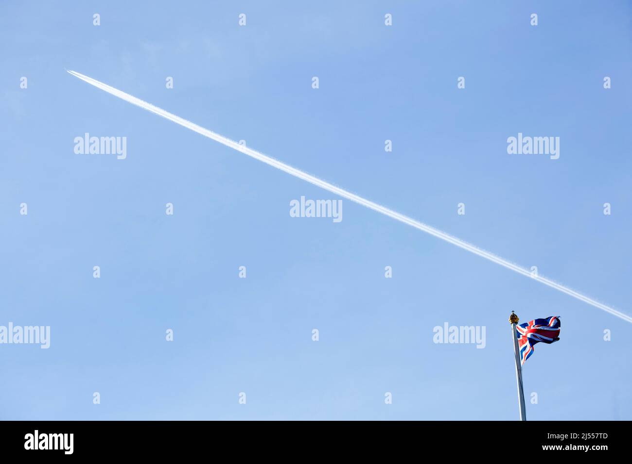 A contrail is seen over a Union flag flying on the roof of Buckingham ...