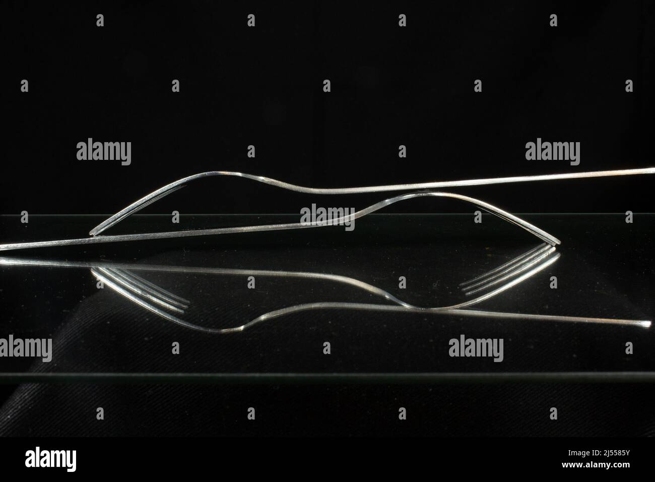 two crossing silver dinner forks both reflected and isolated on a black ...