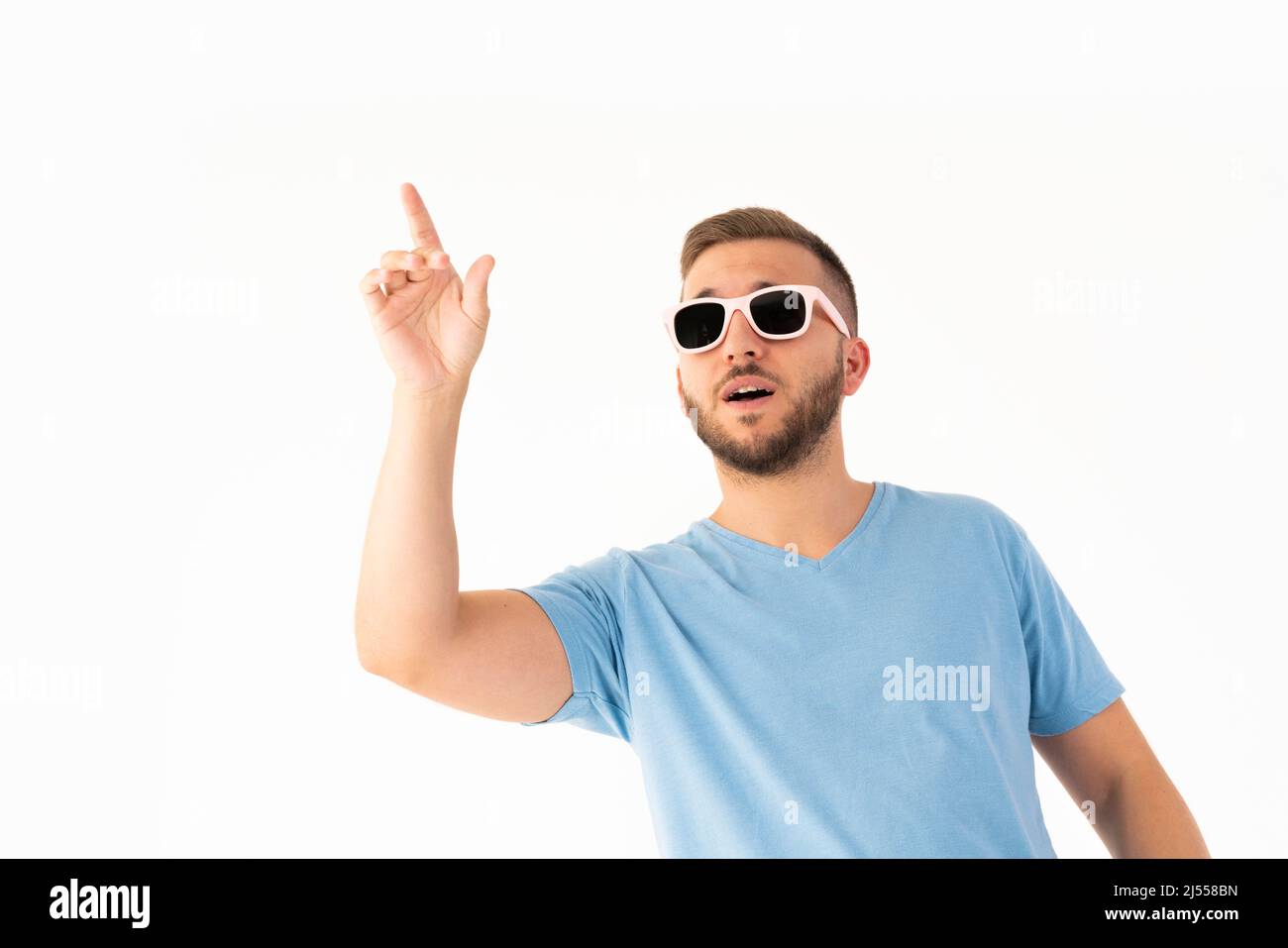 Young man raising his hand up to touch something on a white background ...