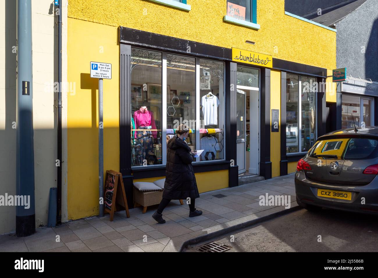 Woman walking past the bright yellow frontage of the Bumblebee shop in ...
