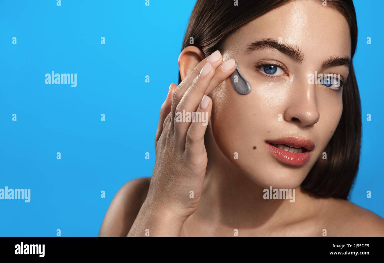 Beautiful girl with dark hair, using face mask on cheek, applying daily ...