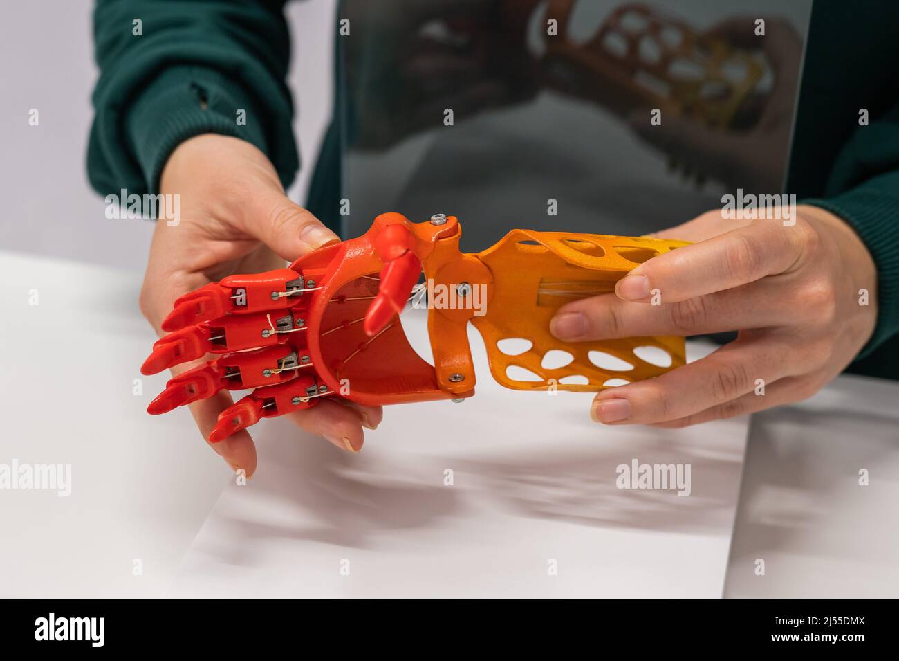 A woman demonstrates a plastic children's prosthetic hand printed on a ...