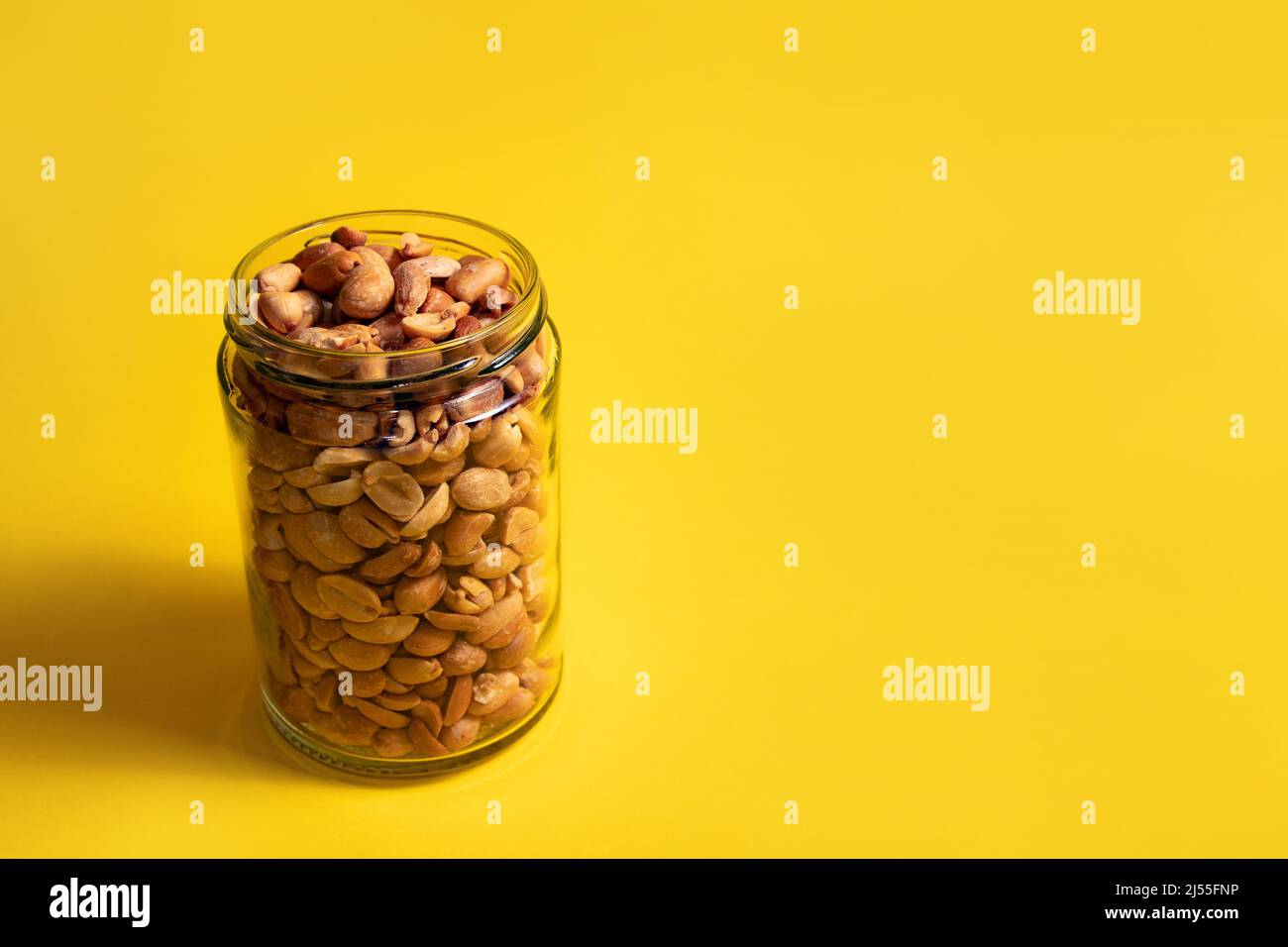 Peanuts in a glass jar on a yellow background Stock Photo - Alamy