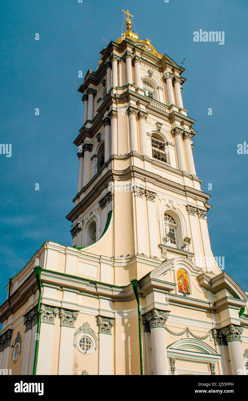 Bell tower of monastery with golden cross on background of blue sky ...