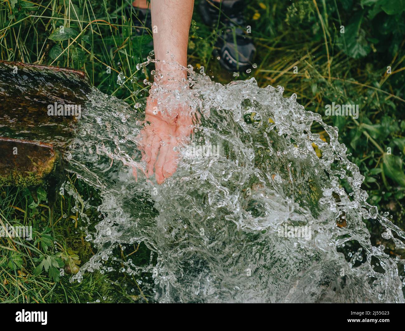 Stream of pure spring water. Human hand in crystal clear cool spring ...