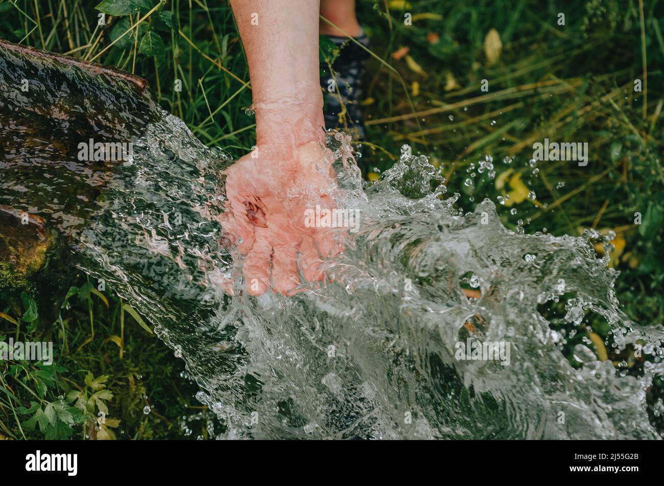 Stream of pure spring water. Human hand in crystal clear cool spring ...