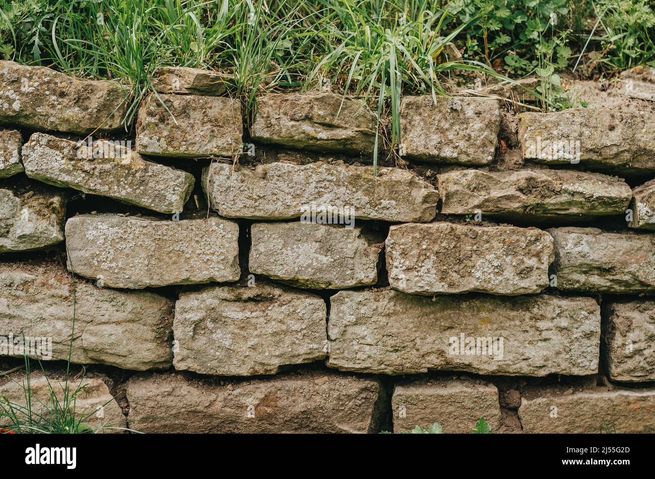 Fence of stone, overgrown with moss and grass. Stone texture. Aged ...