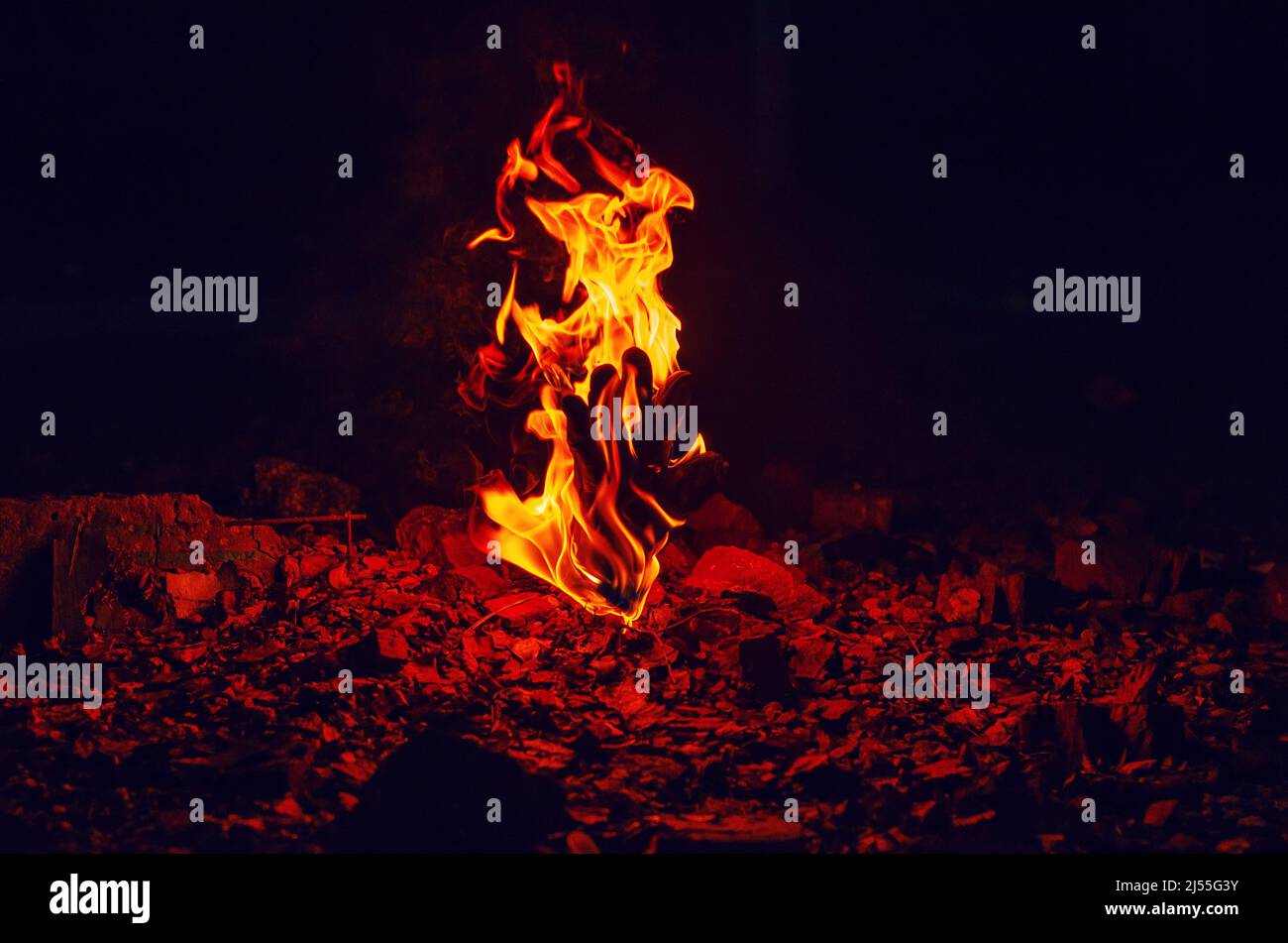 Red flame of burning fire rising from stone covered with autumn leaves ...