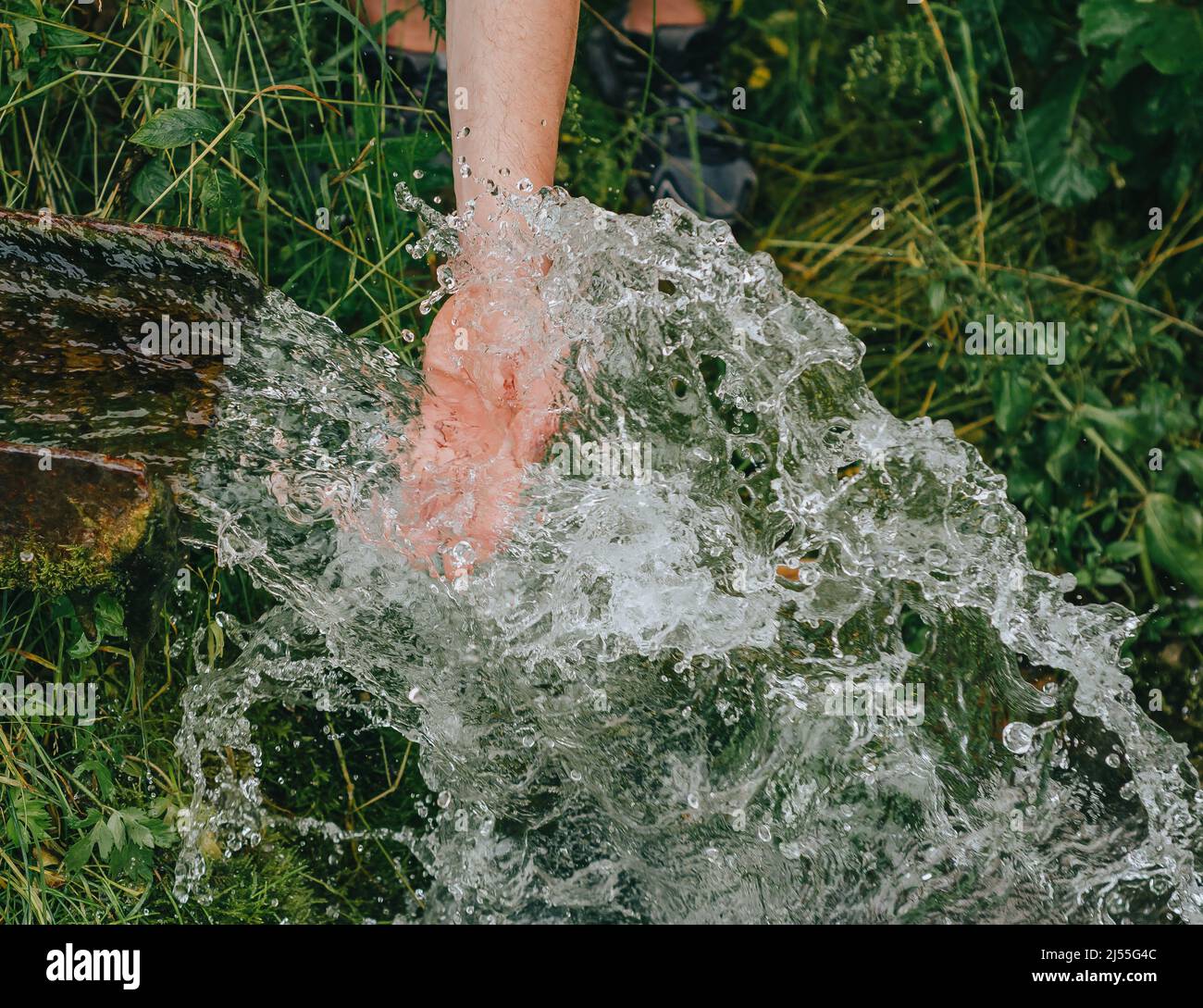 Stream of pure spring water. Human hand in crystal clear cool spring ...