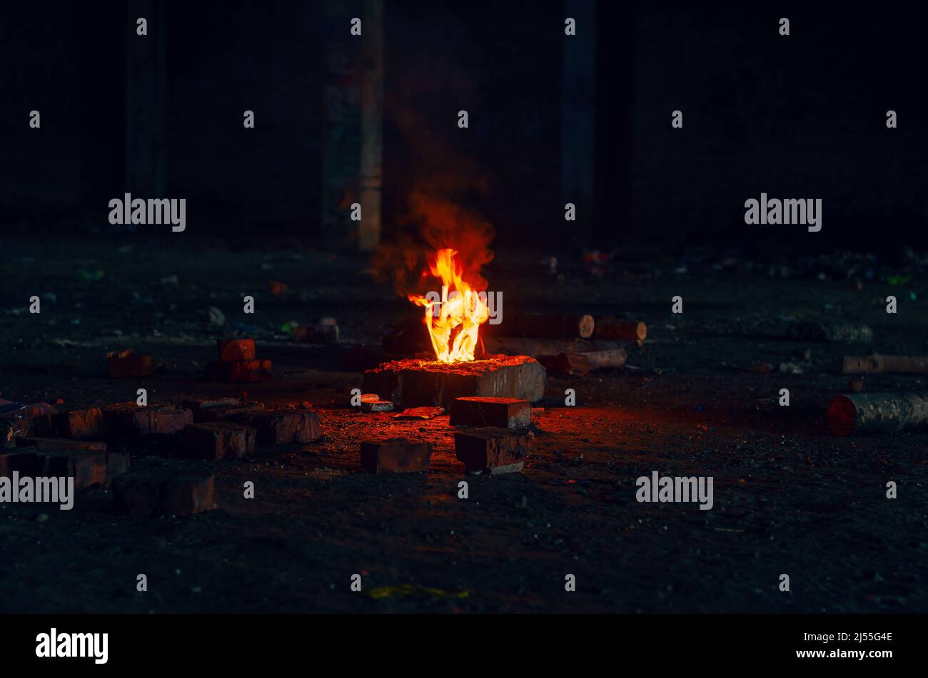Lighting a fire on stone at night. Small red fire, smoke from flames ...