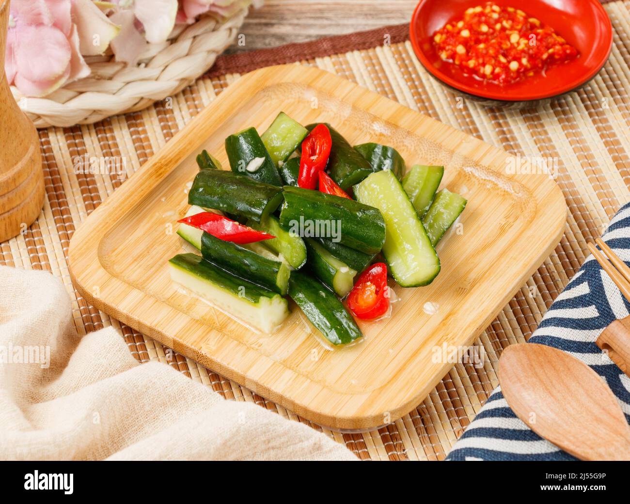 cold cucumber with red chili in a wooden dish with spoon and chopsticks ...
