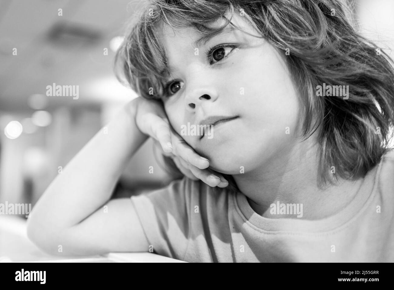 Very unhappy sad kid looks away. Boy waiting for someone in the cafe ...
