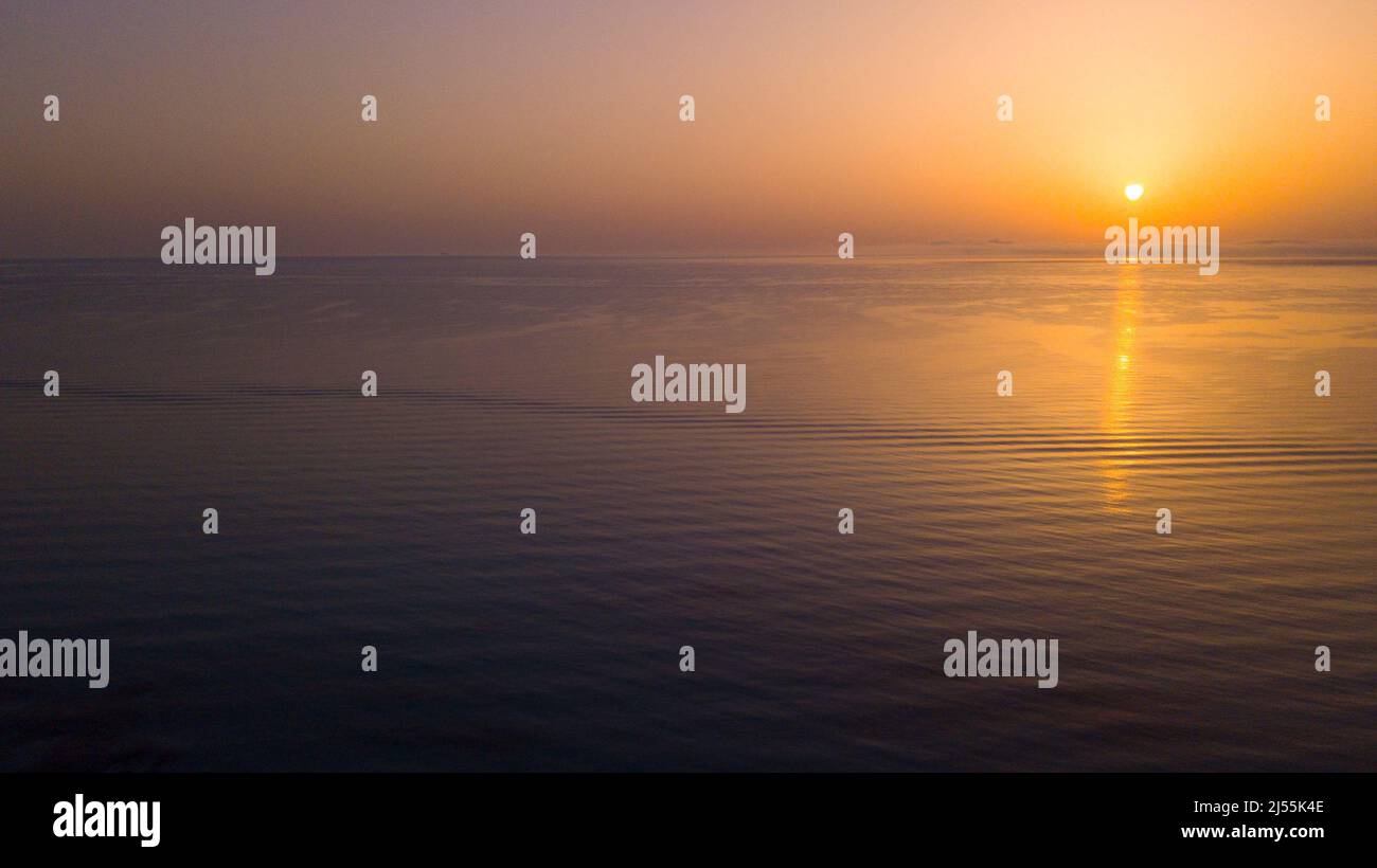 Sunset view on water ocean surface with orange sun in background ...
