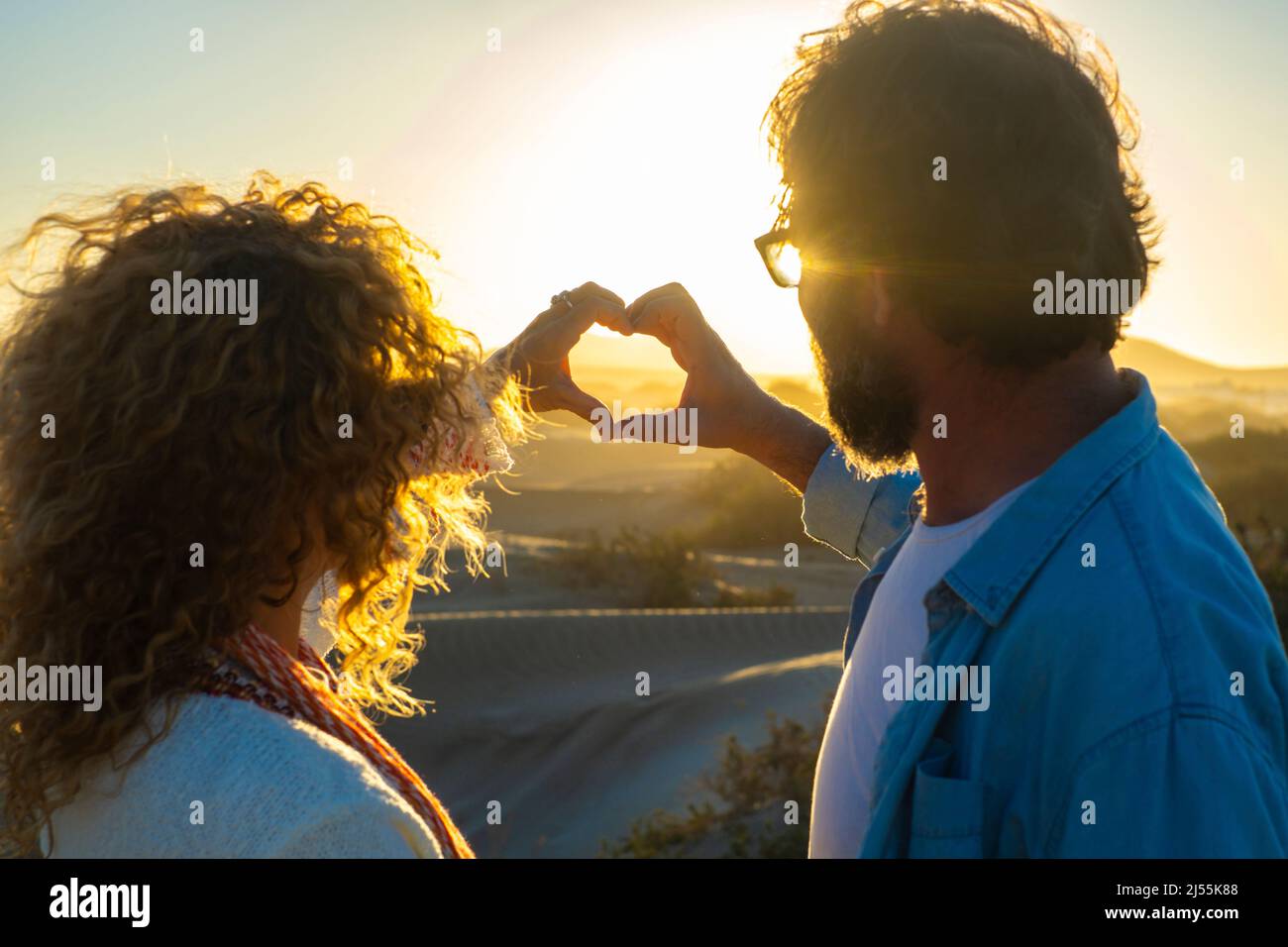 Romantic couple in love doing heart symbol with hands against an ...