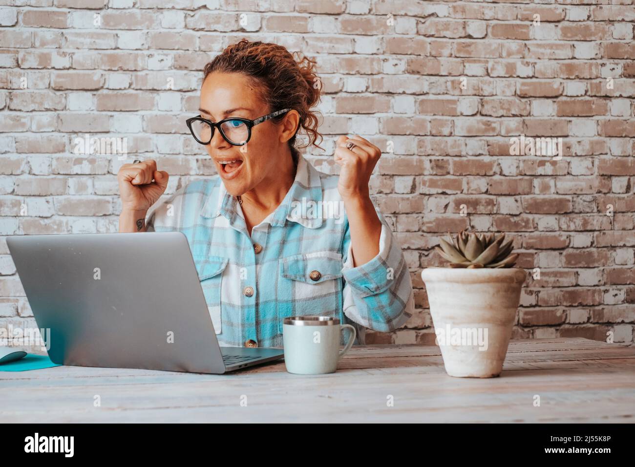 Happy woman exult and celebrate in front of a laptop after receiving a ...
