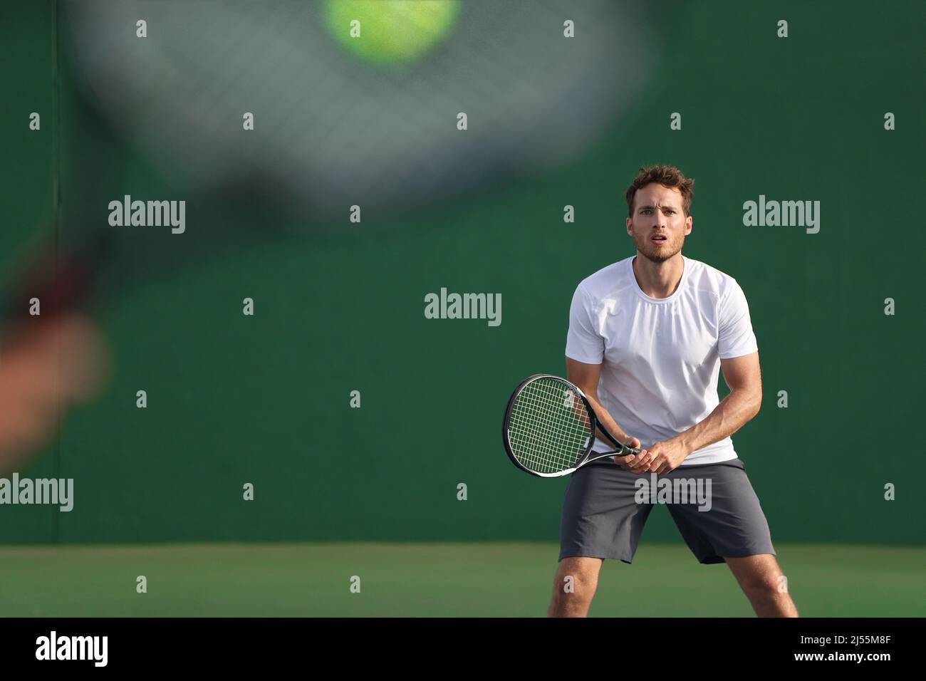 Tennis player focused on other player hitting ball with racket on court ...