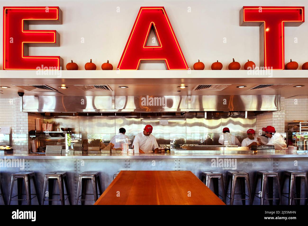 Open kitchen with cooks preparing lunch in a modern diner during fall ...
