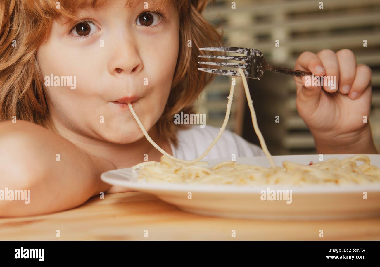 Portrait of a small blond boy eating pasta, spaghetti, closeup. Cute ...