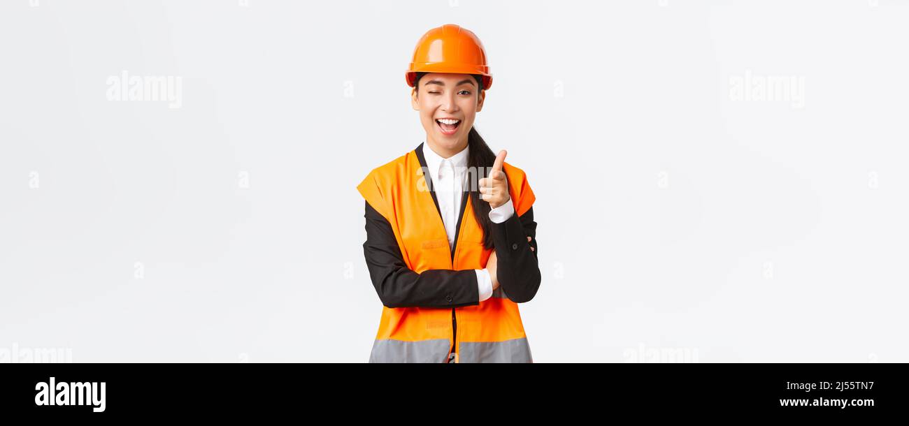 Smiling professional asian female construction manager in safety helmet and reflective jacket ...