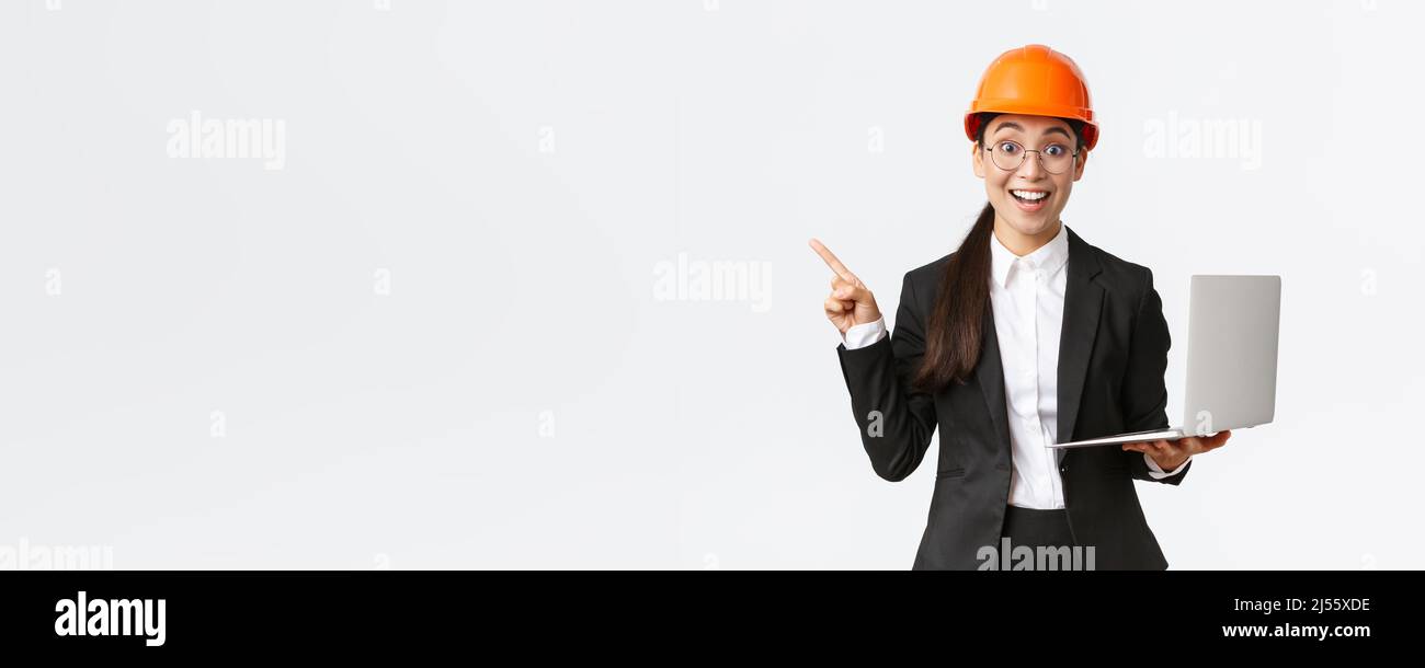 Excited happy asian female engineer, industrial woman in safety helmet ...
