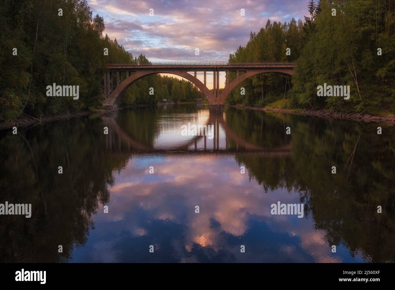 old railway Finnish arch bridge on Janisjoki river in Karelia at sunset ...