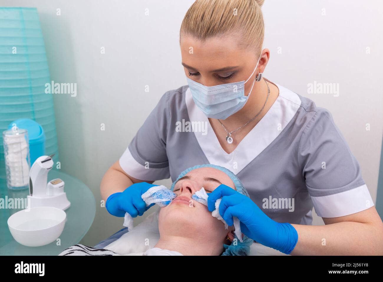 The cosmetologist treats the skin of the face with a tonic in order to ...