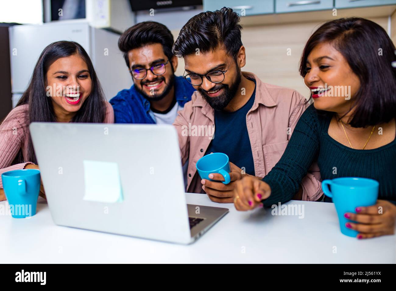 indian four people in kitchen looking at laptop and discussing a ...