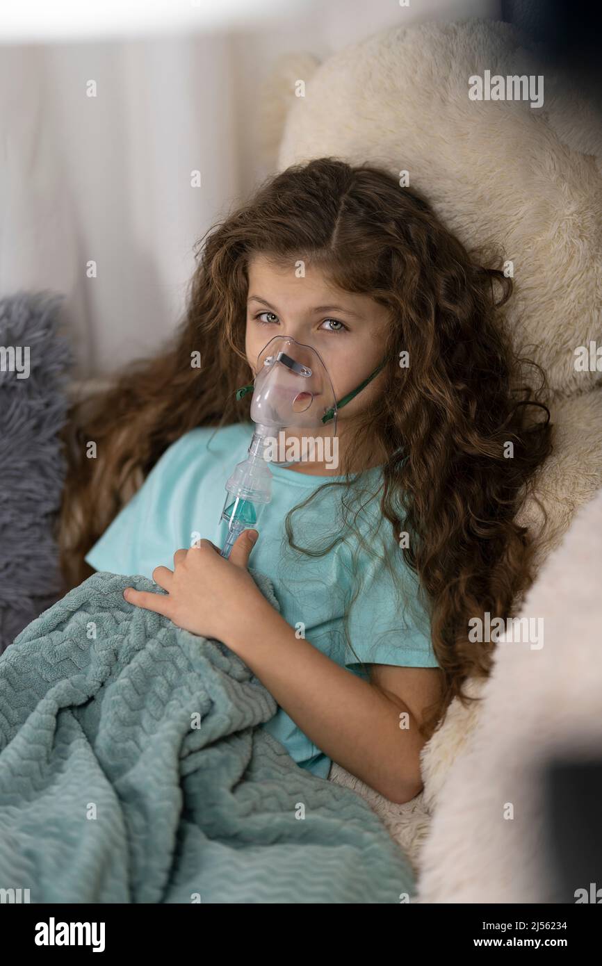 Little girl in an inhalation mask on the bed Stock Photo - Alamy