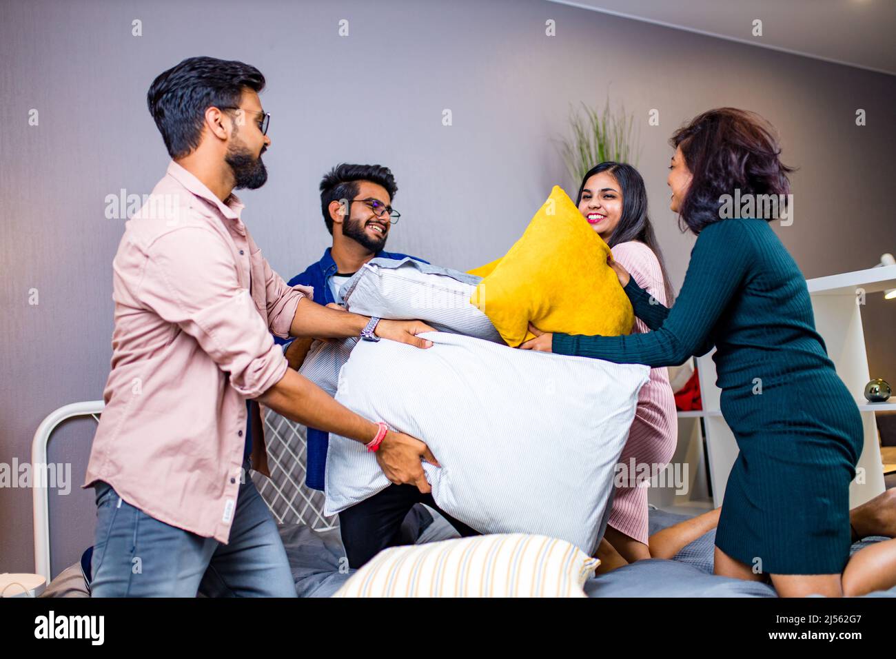 four indian friends fighting pillows at home Stock Photo - Alamy