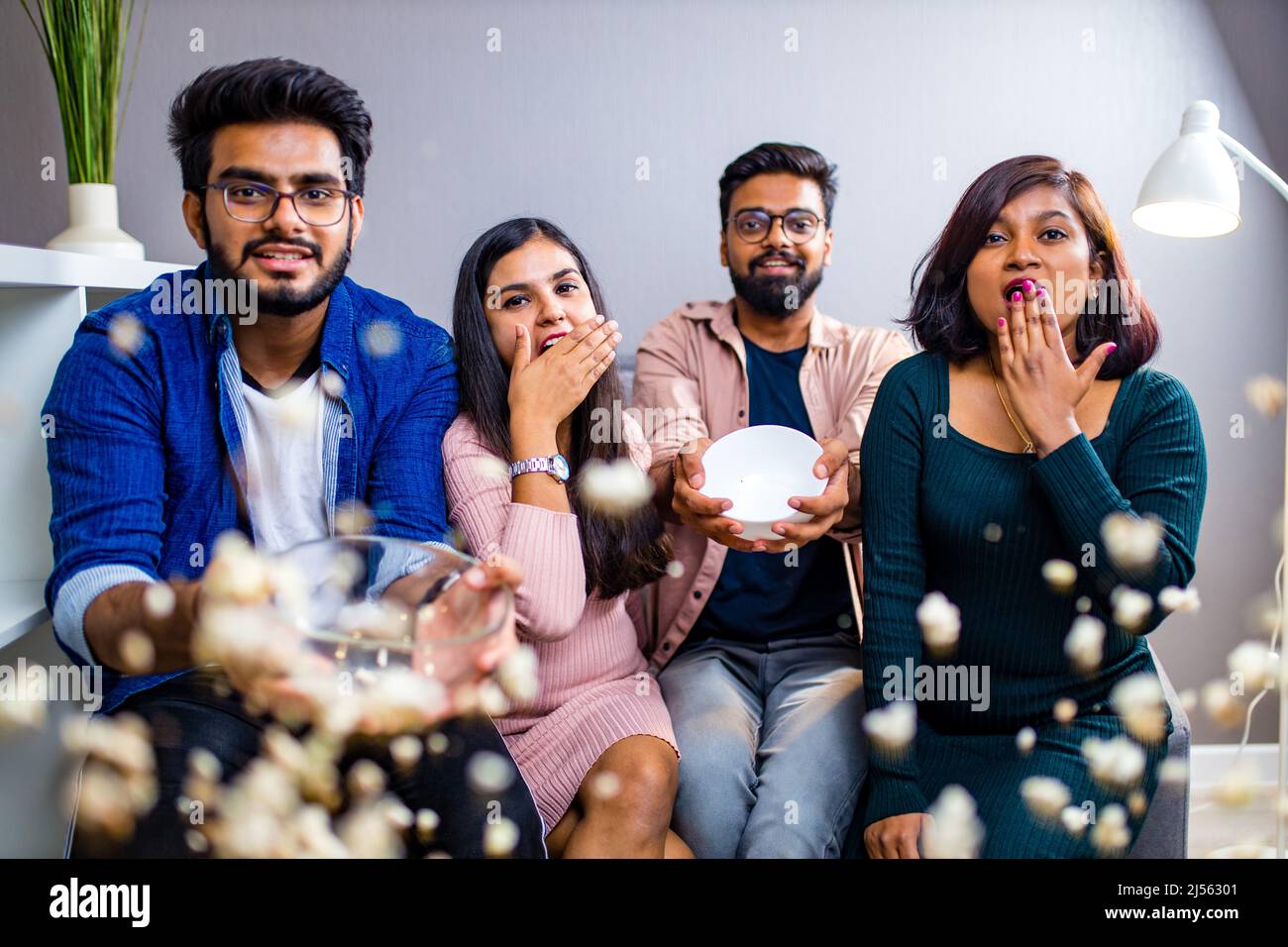 four indian friends watching cinema in the night time at home throwing ...