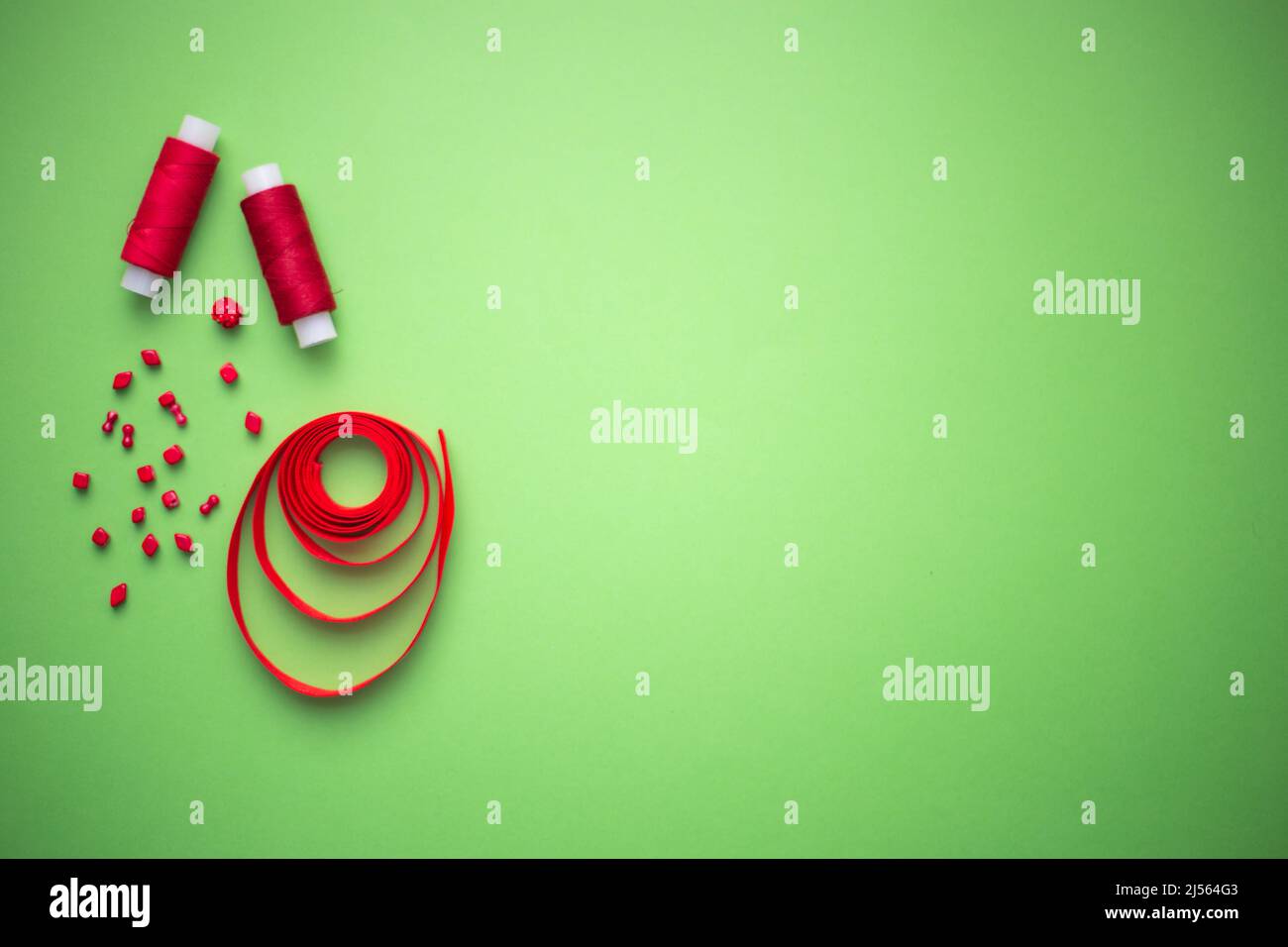 Red threads, red beads and red ribbon on a green background with ...