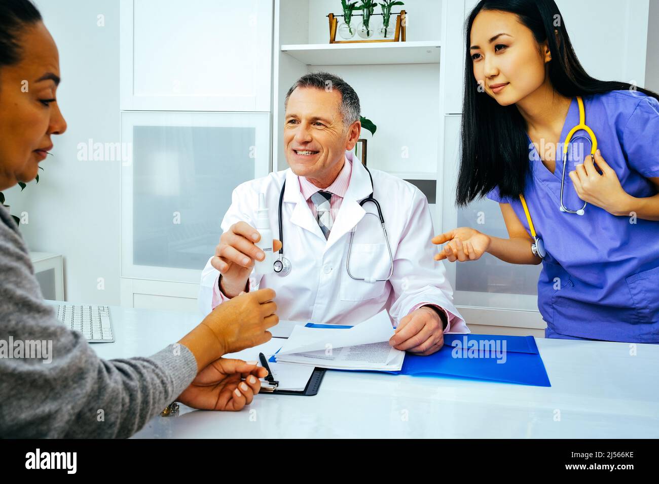smiling doctor physician and nurse practitioner giving nasal spray to ...
