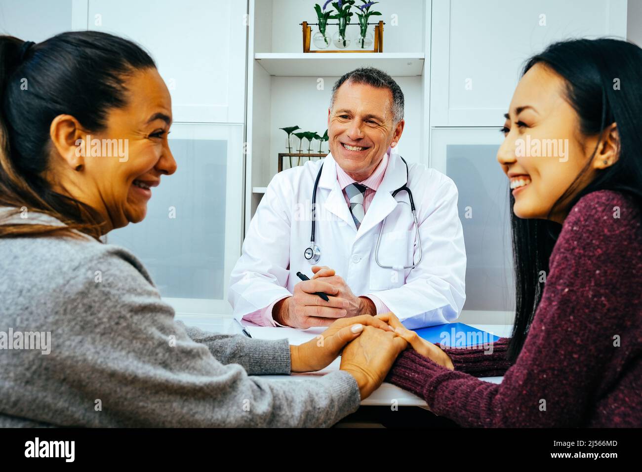 smiling doctor and happy adult female patients in doctor's office ...